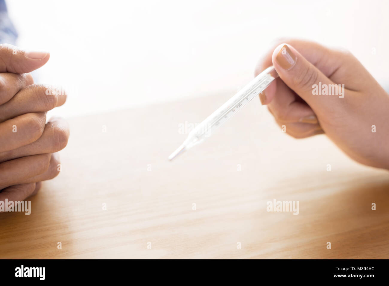 Doctor with a thermometer in his hand taking patient's in hospital ...