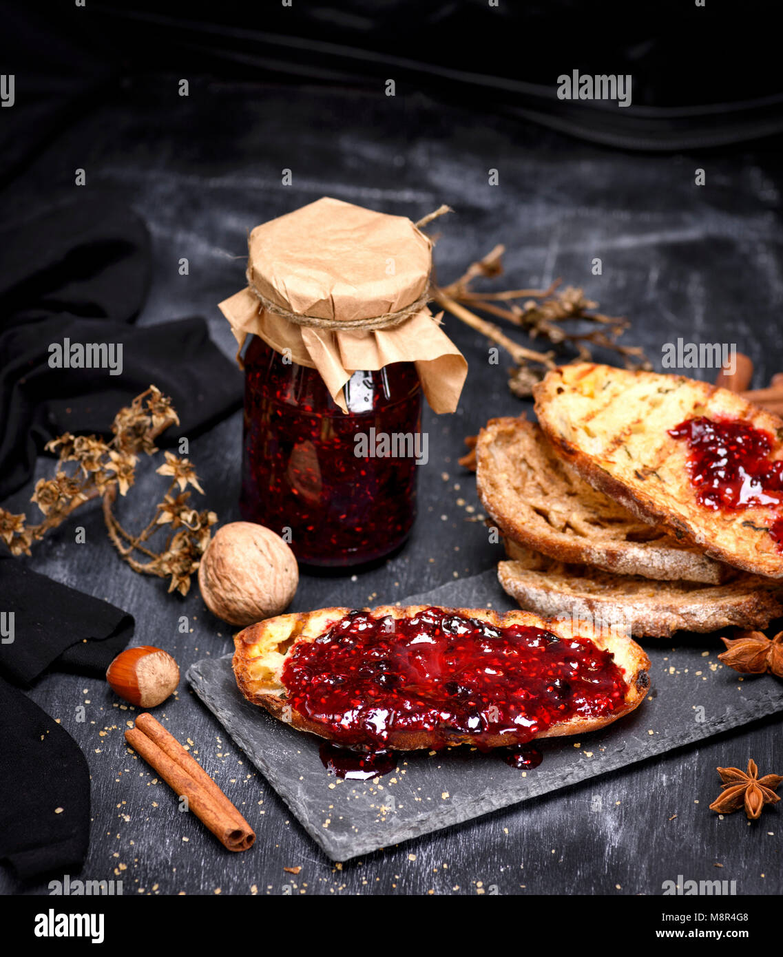 toast of white bread with raspberry jam and a glass jar with jam on a ...