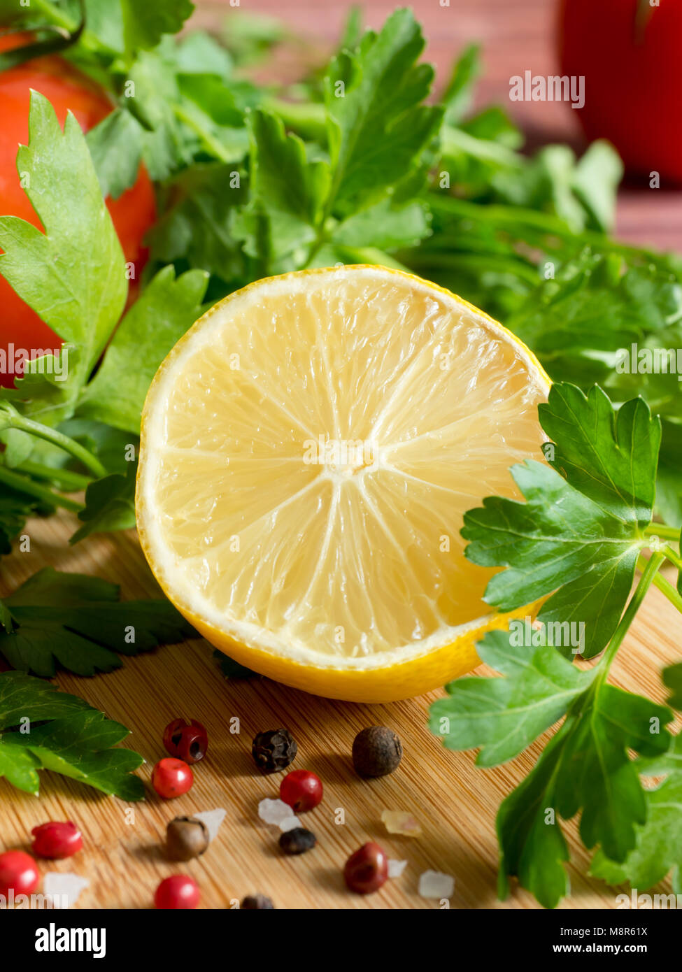 Fresh vegetables Tomatoes Lemon Parsley Pepper coarse Salt on a cutting ...