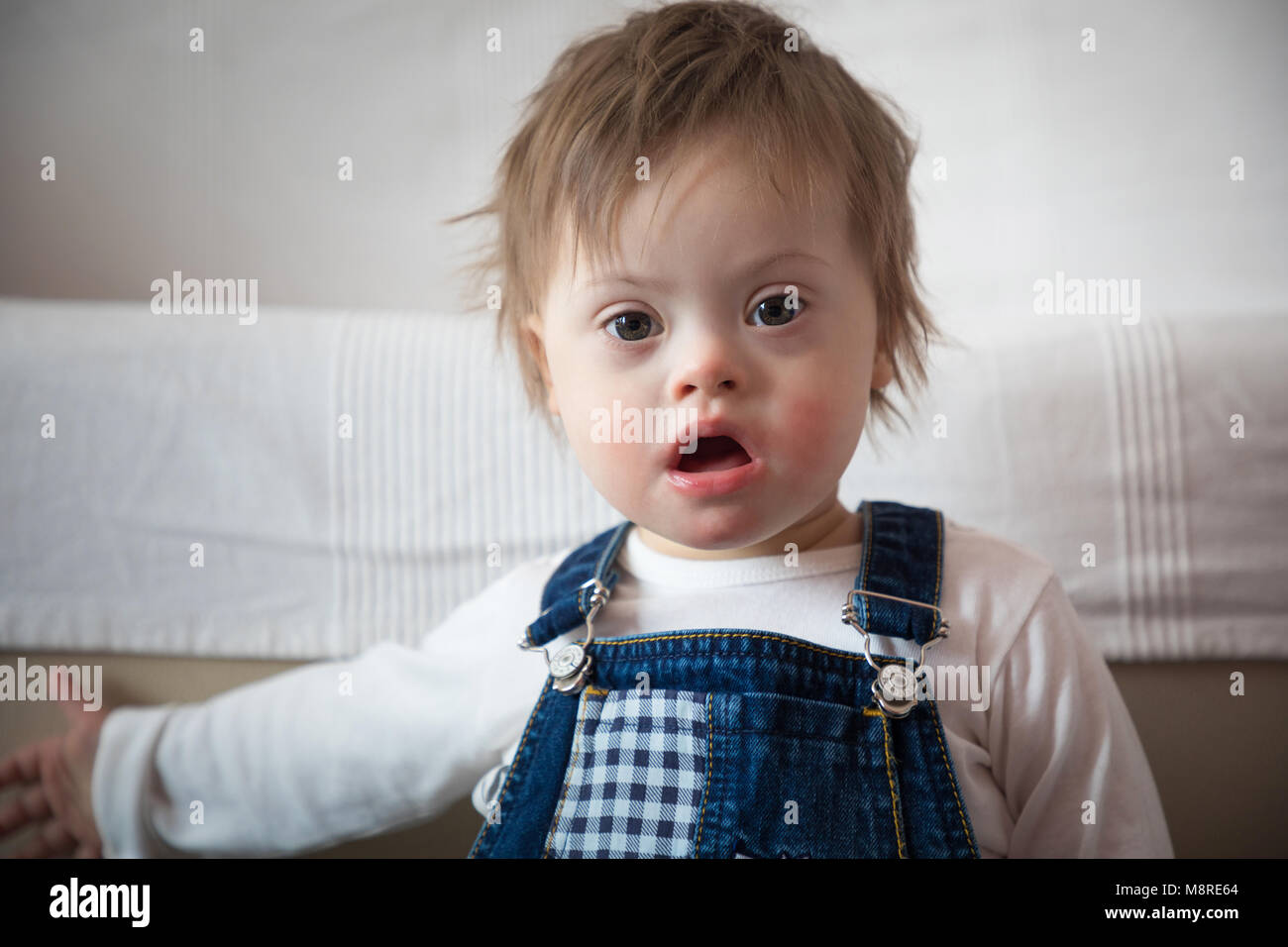 Portrait of cute baby boy with Down syndrome in home living room Stock ...