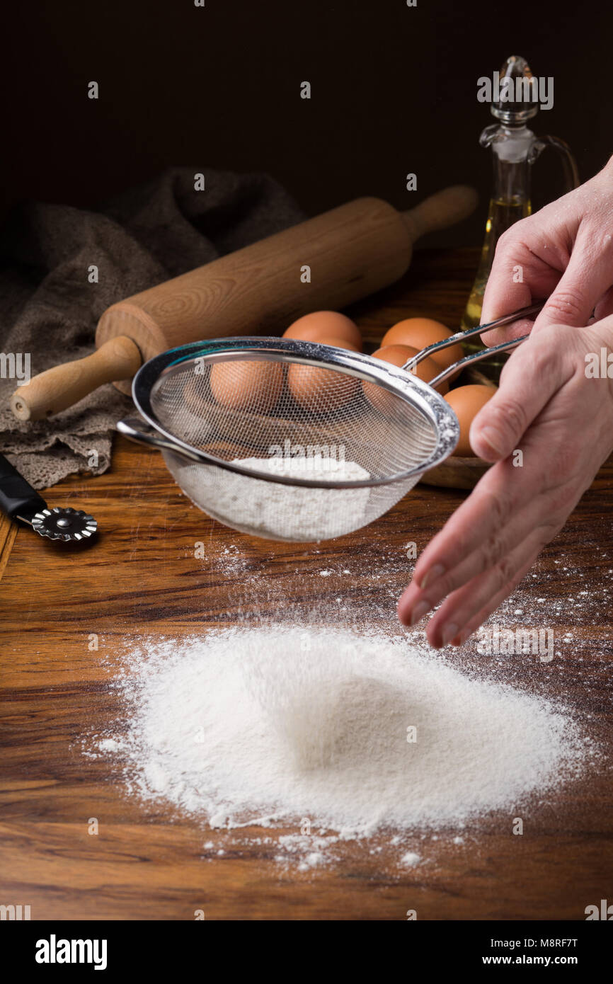 sifting flour from a strainer on a wooden table Stock Photo - Alamy