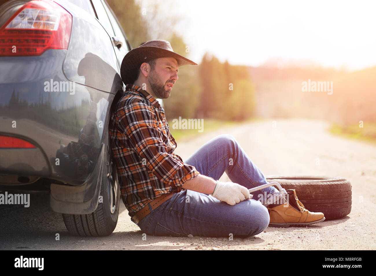 Man is sitting on the road by the car Stock Photo - Alamy