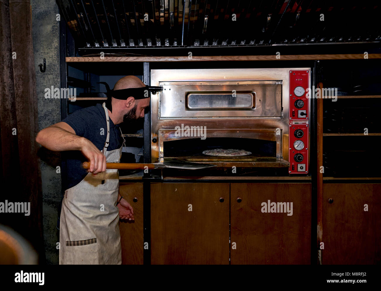 man pulls the pizza out of the oven Stock Photo - Alamy