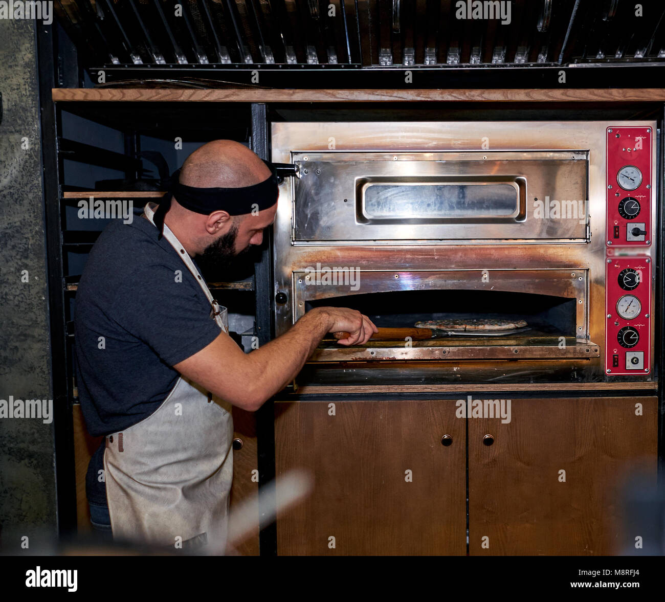 man pulls the pizza out of the oven Stock Photo - Alamy