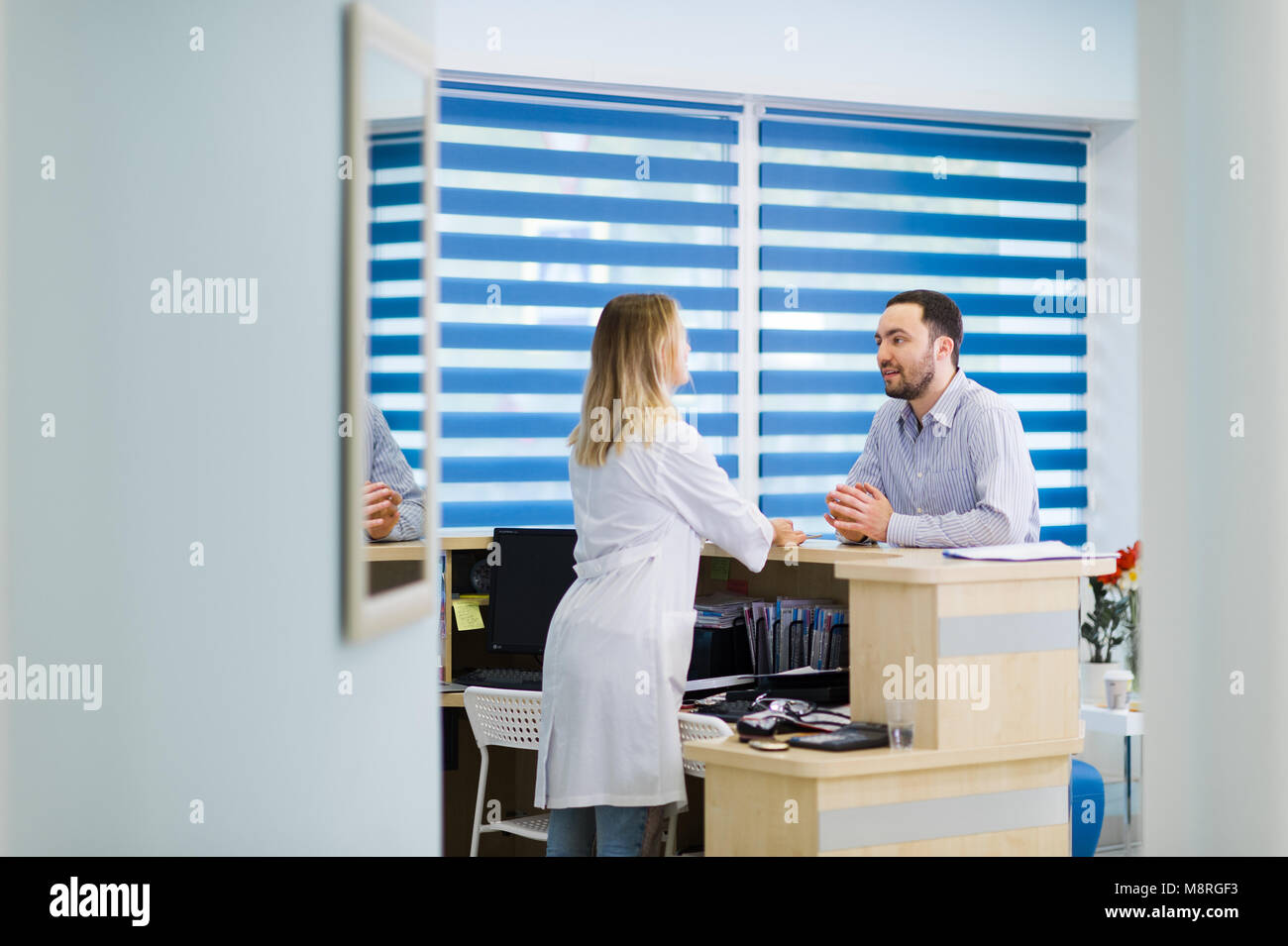 Nurse and patient conversing at reception desk in hospital Stock Photo ...