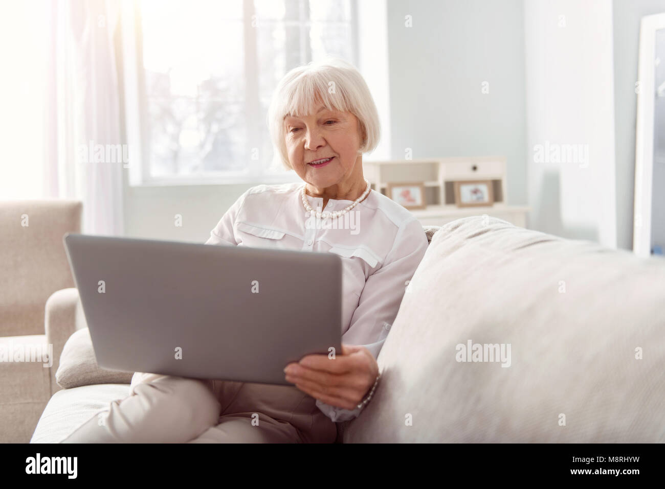 Charming elderly woman reading email on her laptop Stock Photo - Alamy
