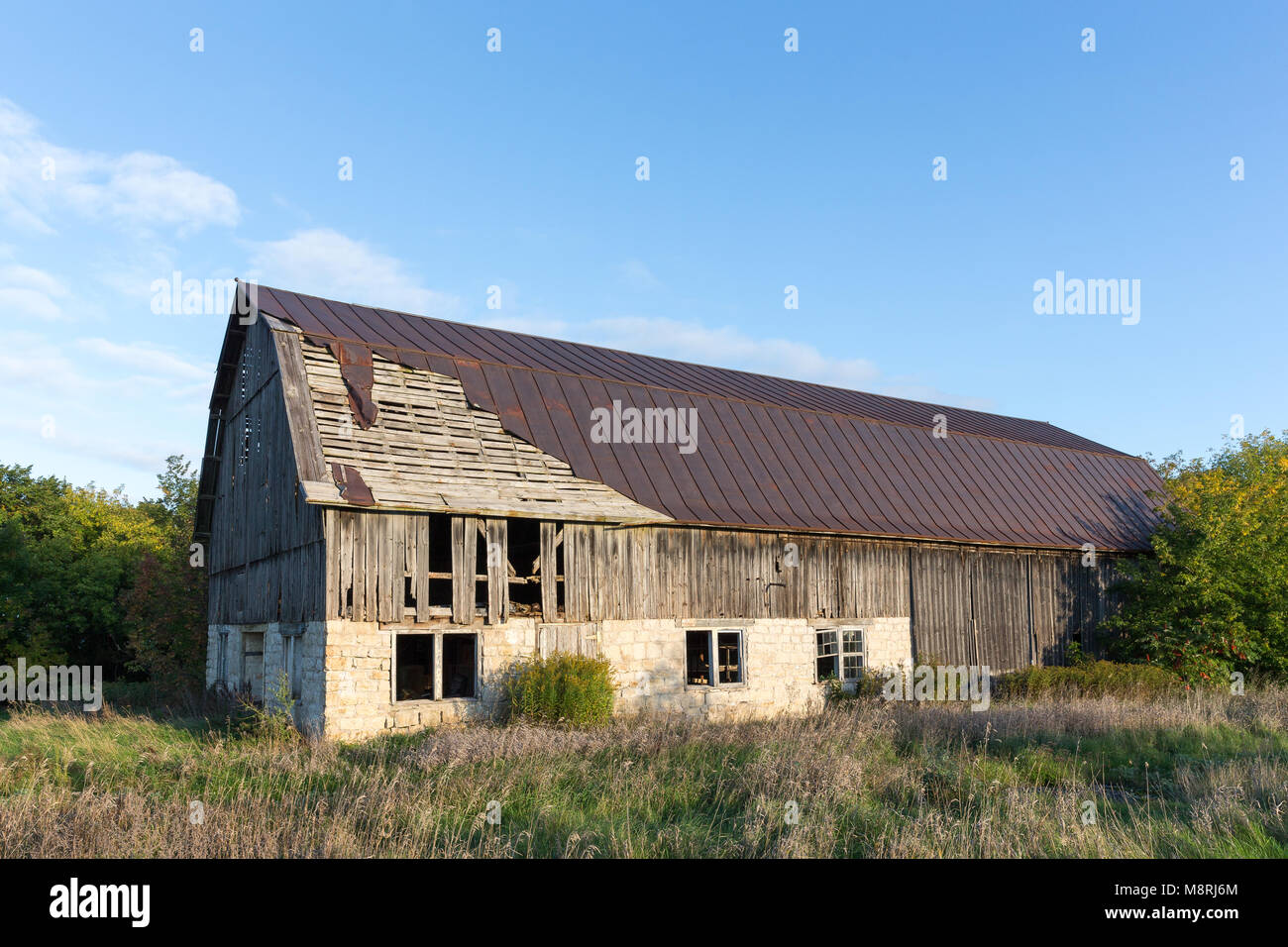 Abandoned and dilapidated barn set against a blue sky. Concepts could ...