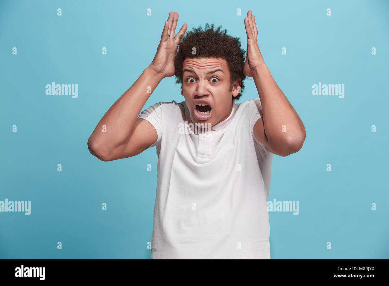 The young emotional angry man screaming on blue studio background Stock ...