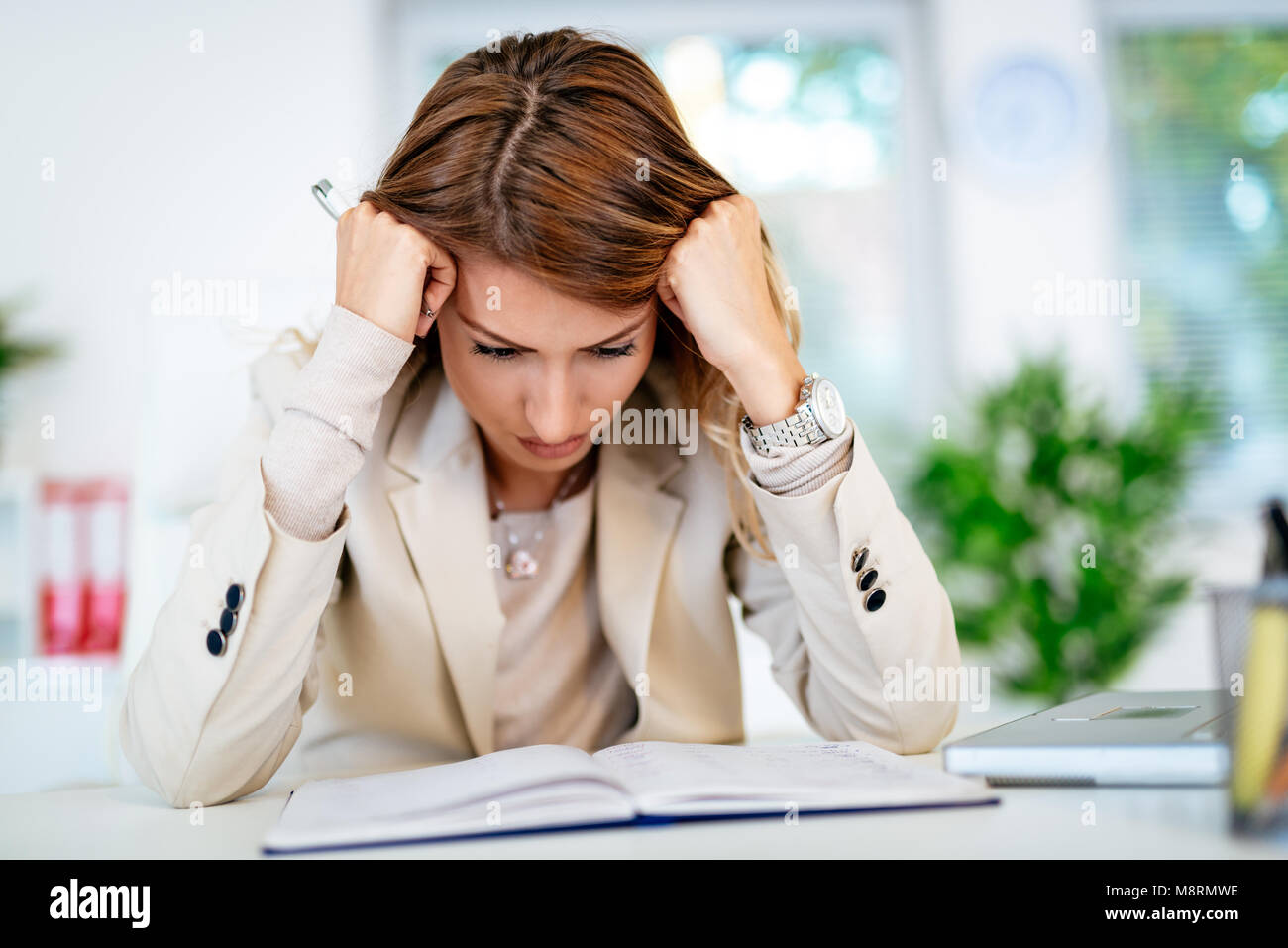 Frustrated young businesswoman sitting in the office and worriedly ...