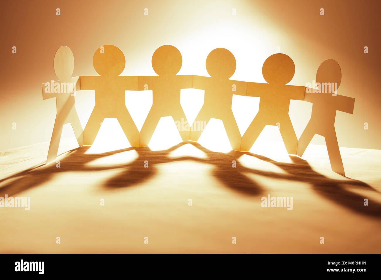 Team of paper chain people in a row holding hands Stock Photo - Alamy