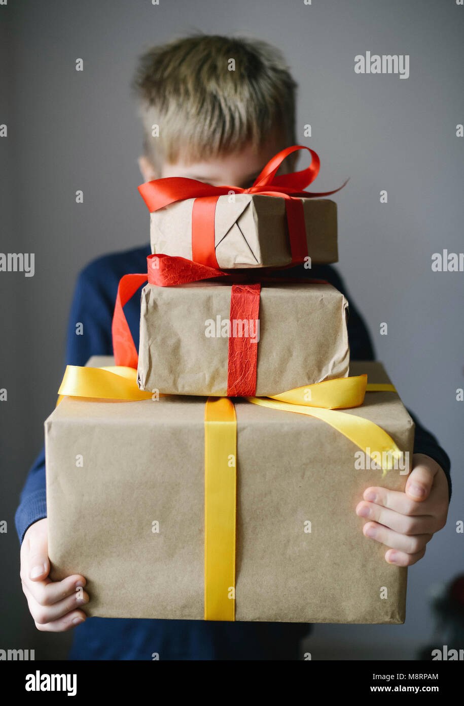 Boy carrying wrapped gifts at home Stock Photo - Alamy