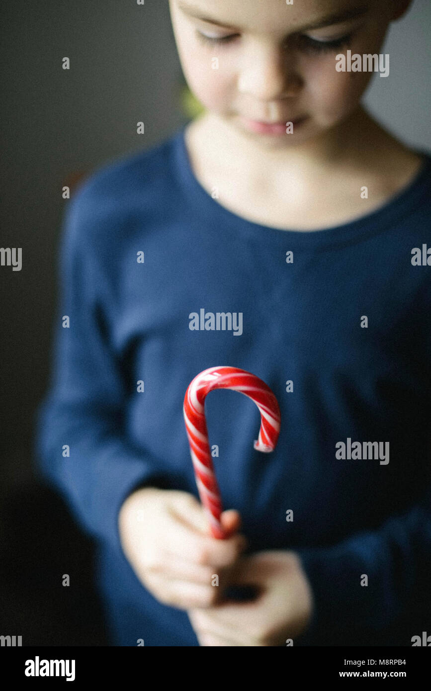 Boy holding candy cane at home Stock Photo - Alamy