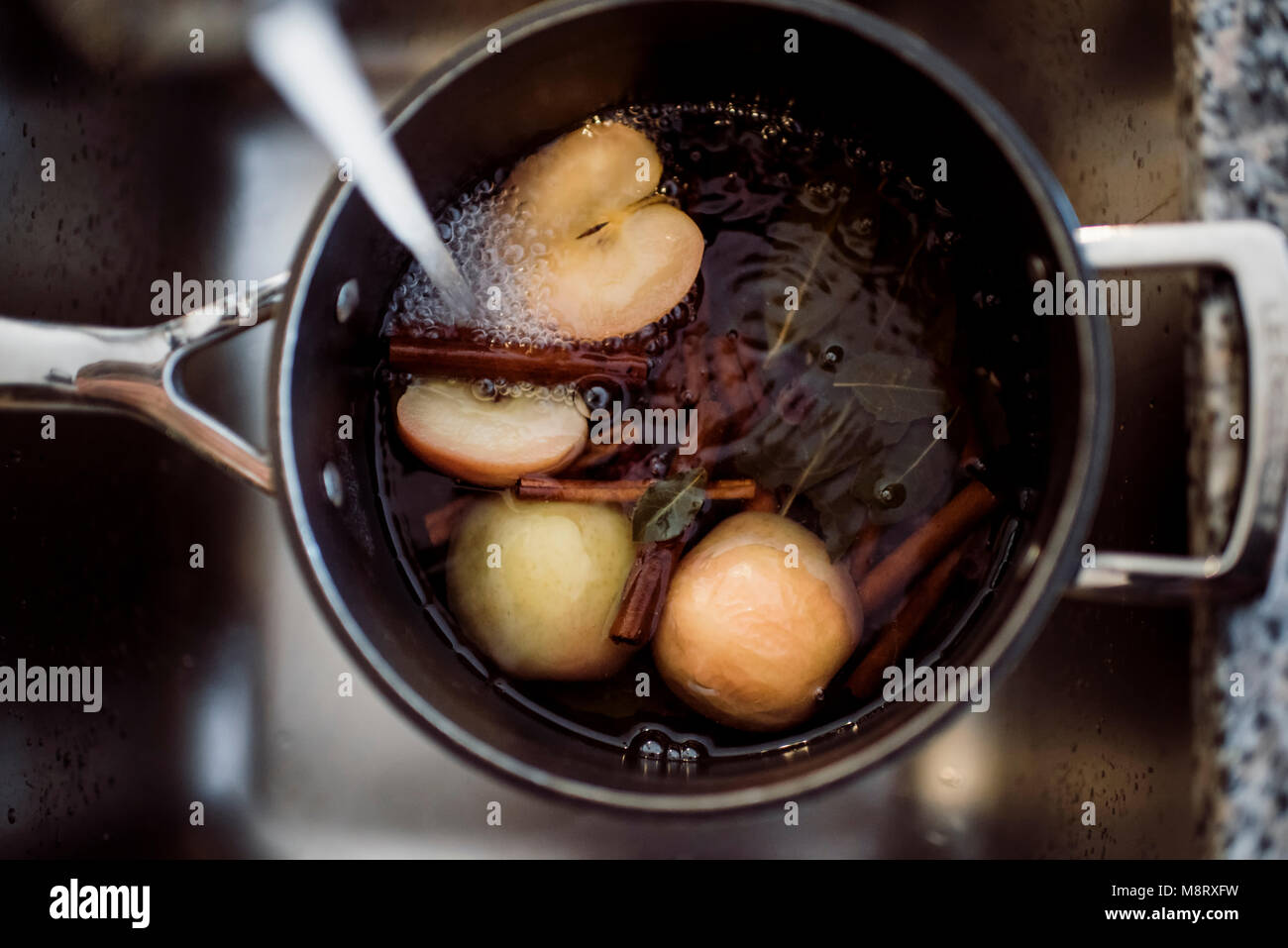 Close-up of apples with cinnamon and herbs being washed in container ...