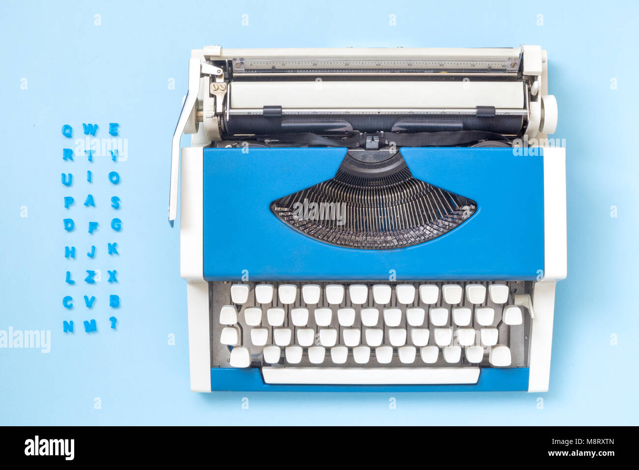Typewriter with blank keyboard and letters next to it on pastel blue ...