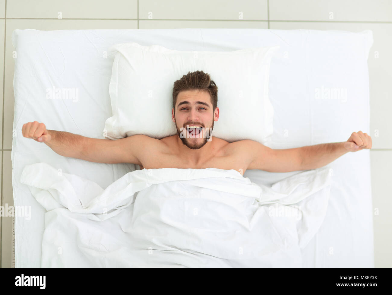top view. happy man waking up in a comfortable bed Stock Photo - Alamy