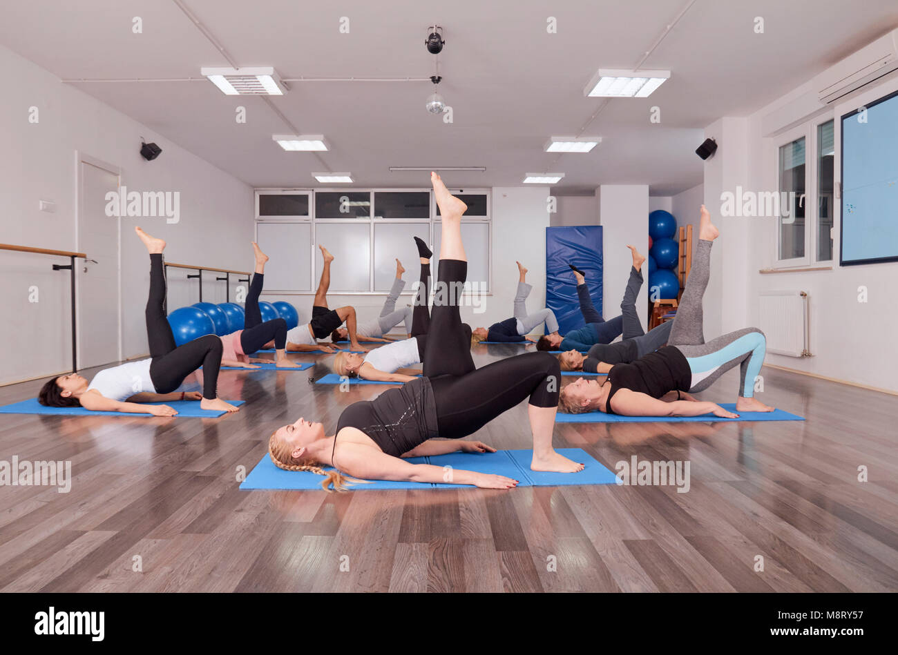 Group of people lying on exercise mats while exercising in pilates ...