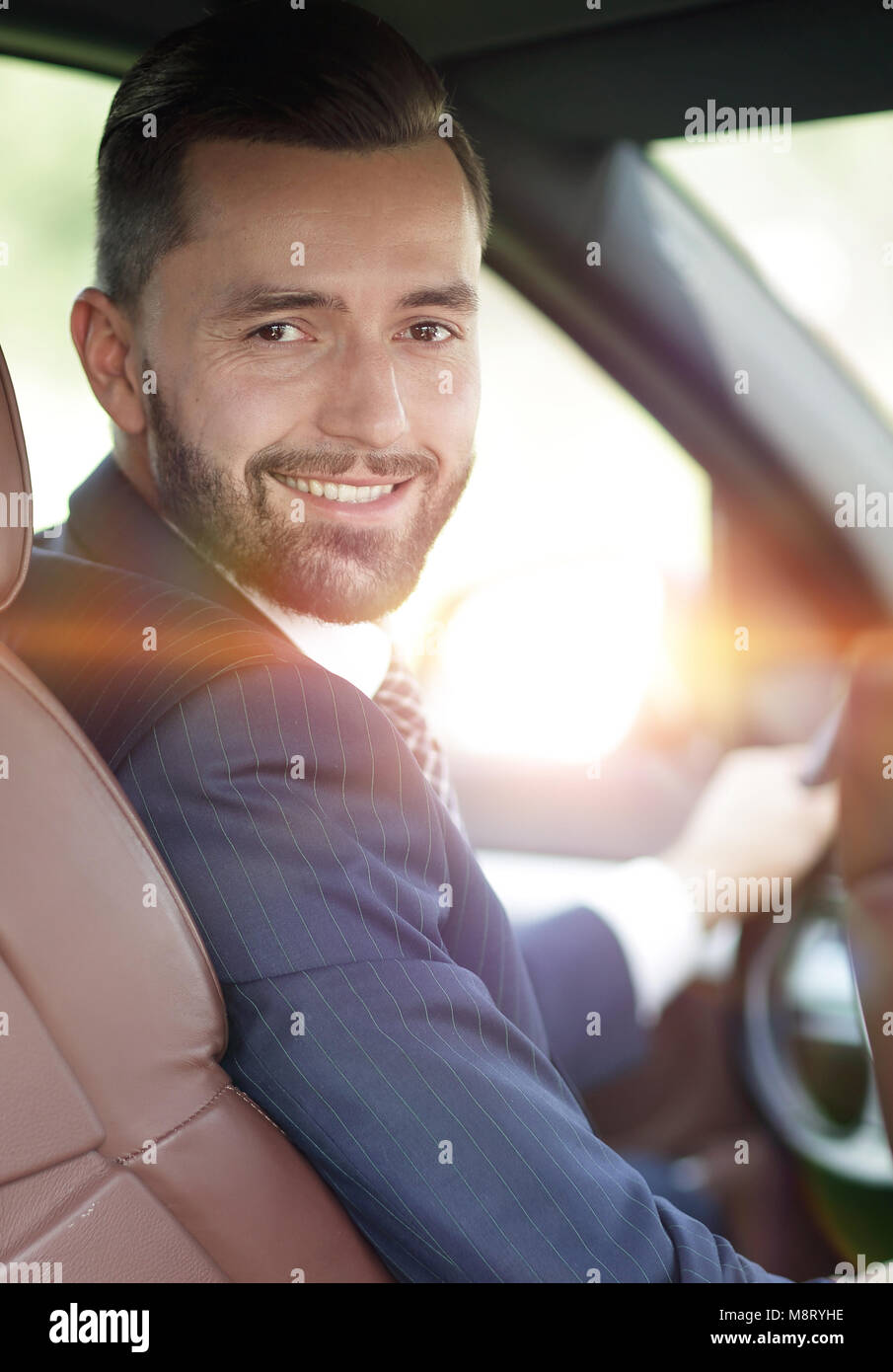 Handsome young man sitting in the front seat of a car looking at the ...