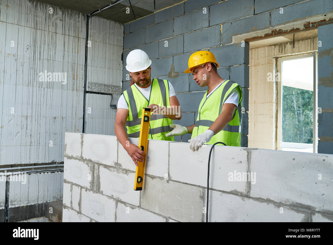 Two Construction Workers Building Wall Stock Photo - Alamy