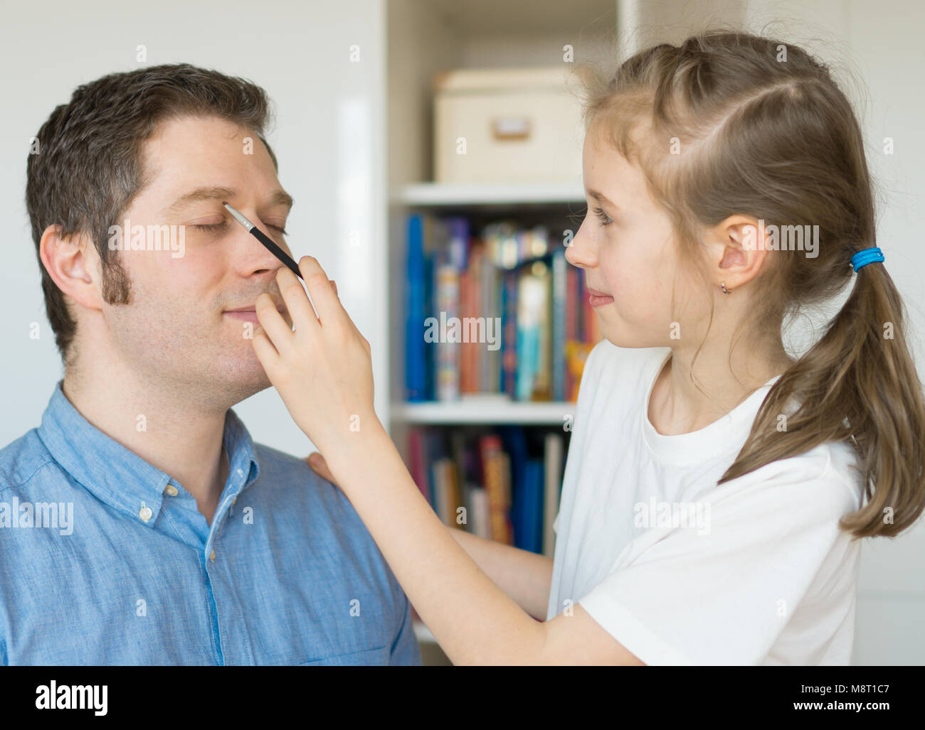 Cute little girl making makeup to her dad Stock Photo - Alamy