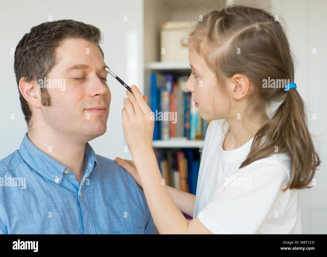 Cute little girl making makeup to her dad Stock Photo - Alamy