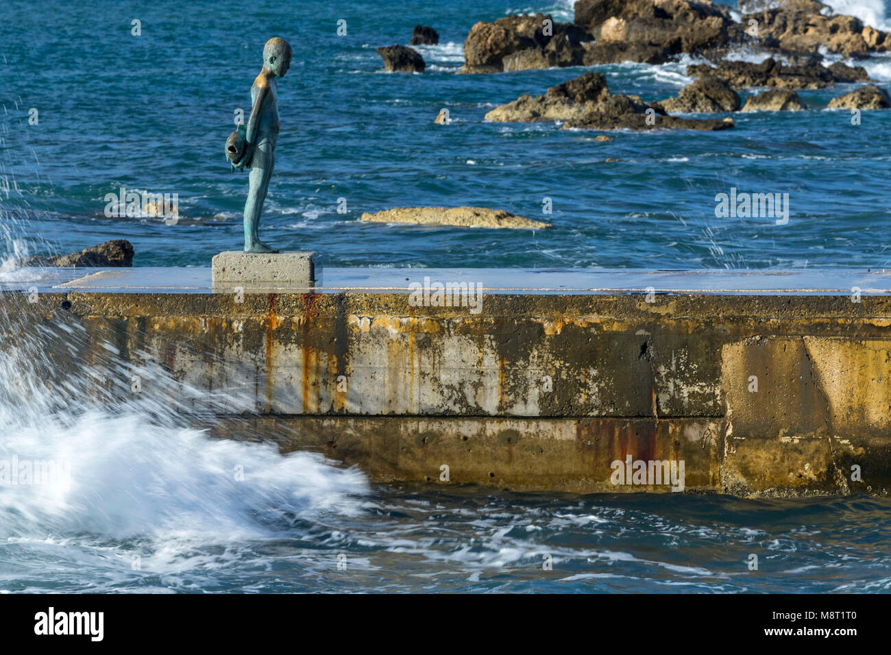 Boy with fish statue in Paphos Harbour in the spring sunshine with blue ...