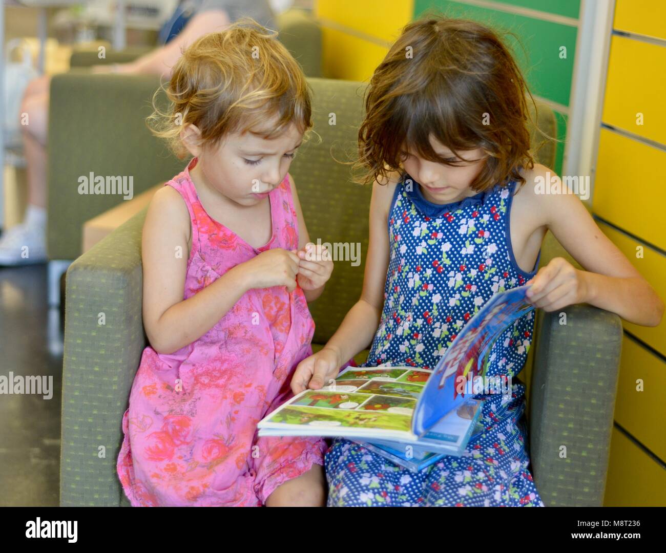 Two girls reading a book in a public library, CityLibraries Aitkenvale ...