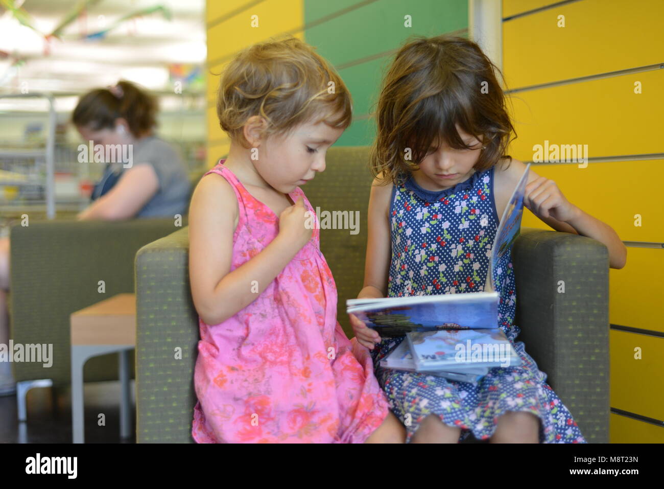 Two girls reading a book in a public library, CityLibraries Aitkenvale ...