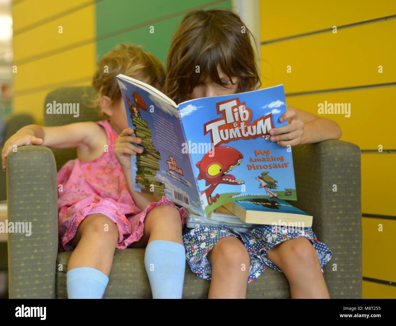Two girls reading a book in a public library, CityLibraries Aitkenvale ...