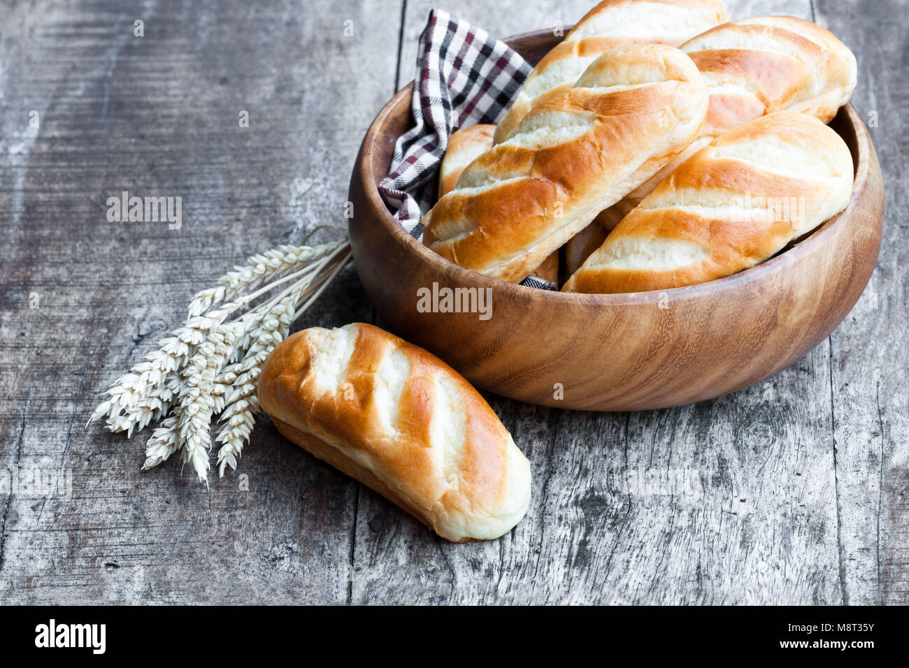 Mini loaf bread in wooden bowl and wheat ears on wooden table Stock ...