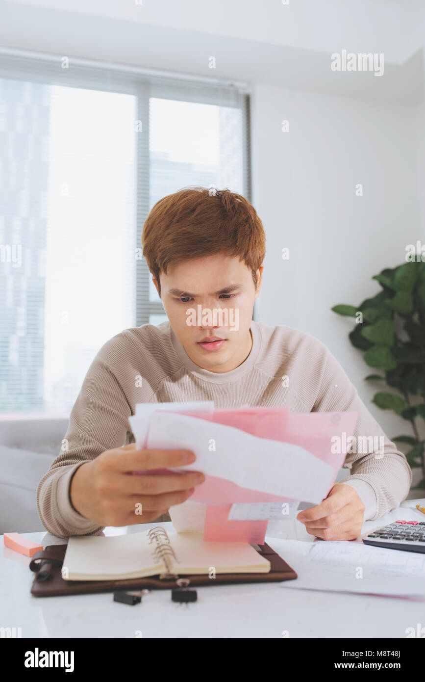 Asian young man counting using calculator and stress in problem with ...