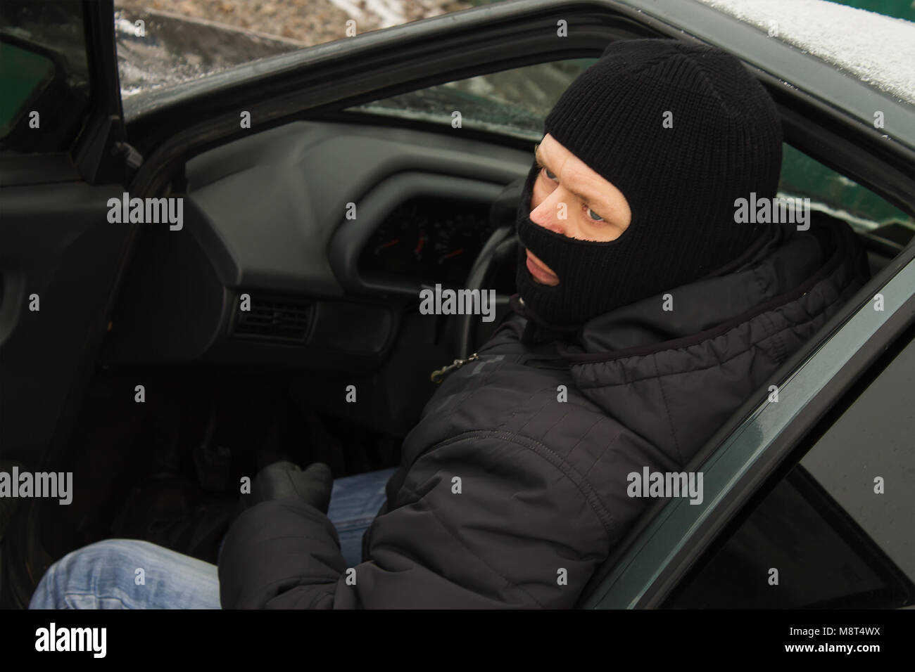 criminal in a mask hijacks the car. car theft Stock Photo - Alamy