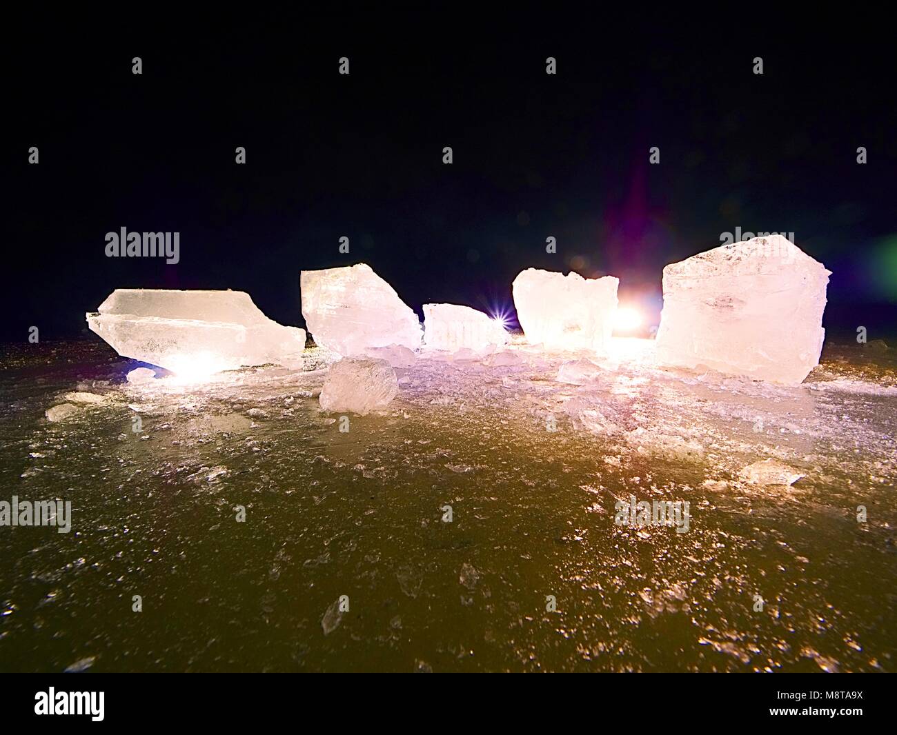Melting pieces of chopped ice blocks. Strong colorful backlight shine ...
