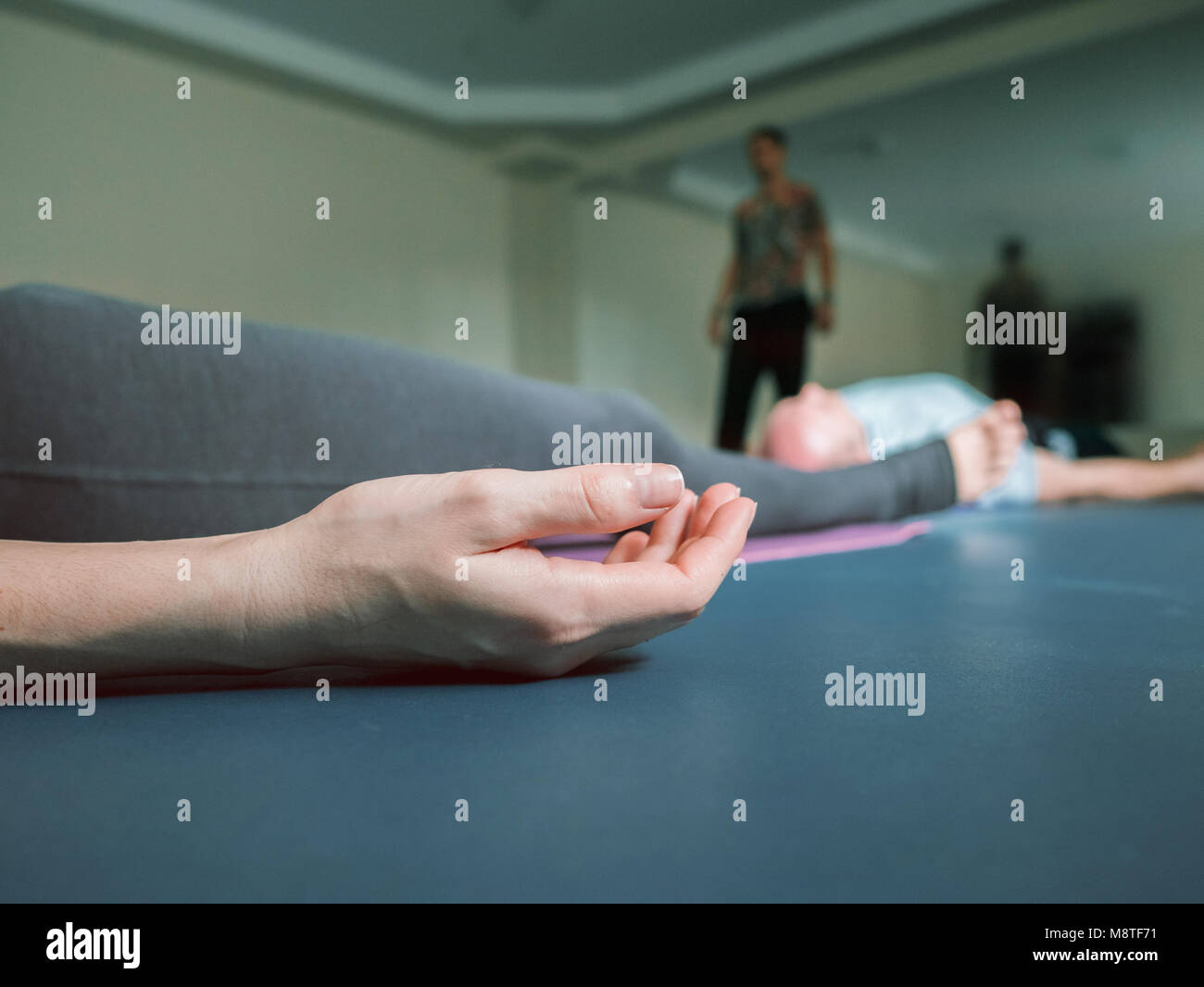 Group of young sporty people practicing yoga lesson with instructor in ...