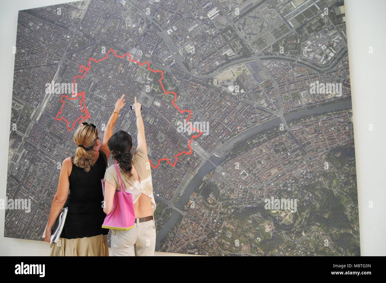 Two women standing back view in front of huge billboard aerial view of ...