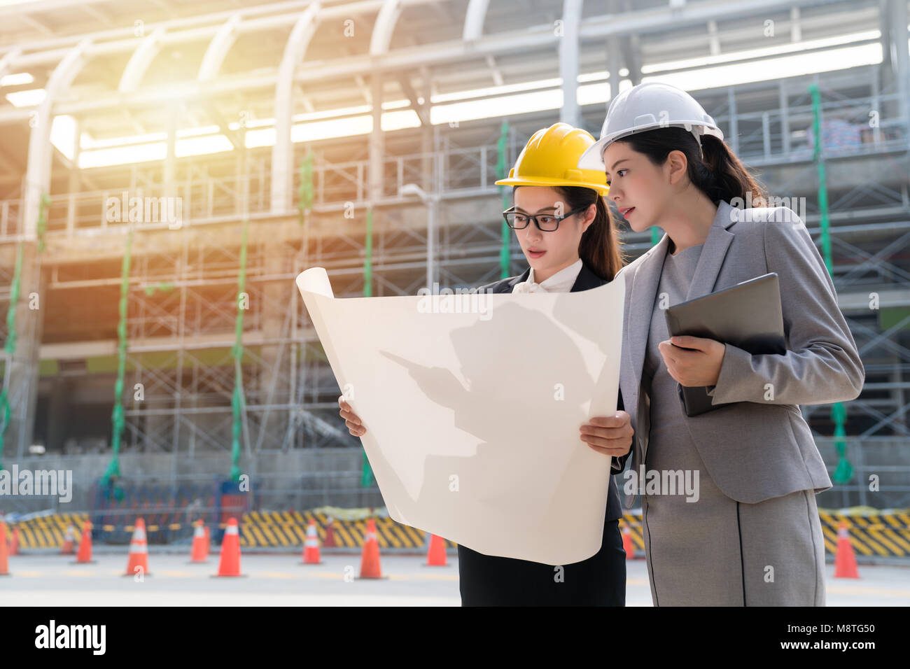 Two female engineers checking construction plan on site. Seriously ...