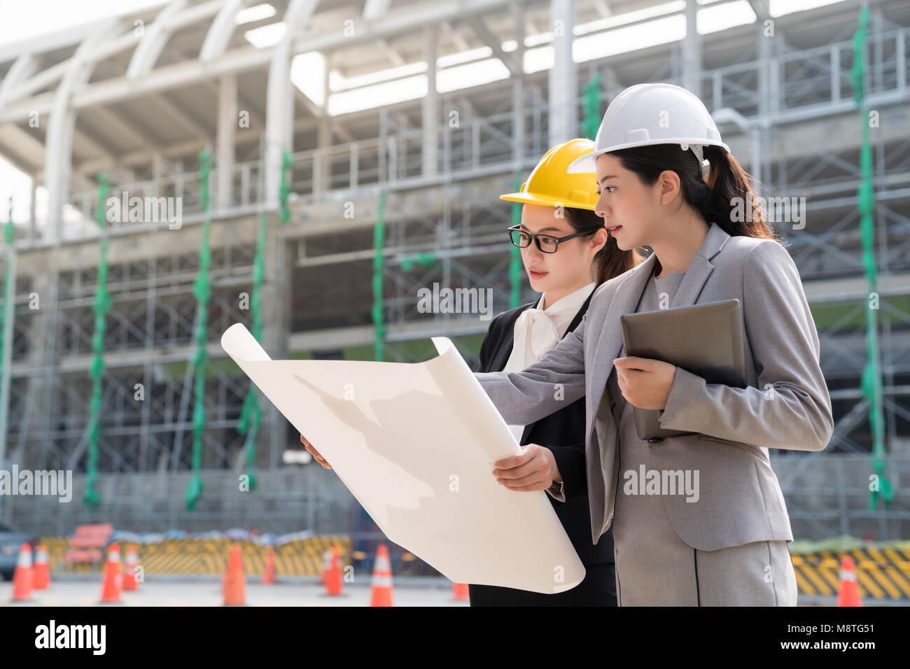 A female engineer displaying a building plan to another woman architect ...
