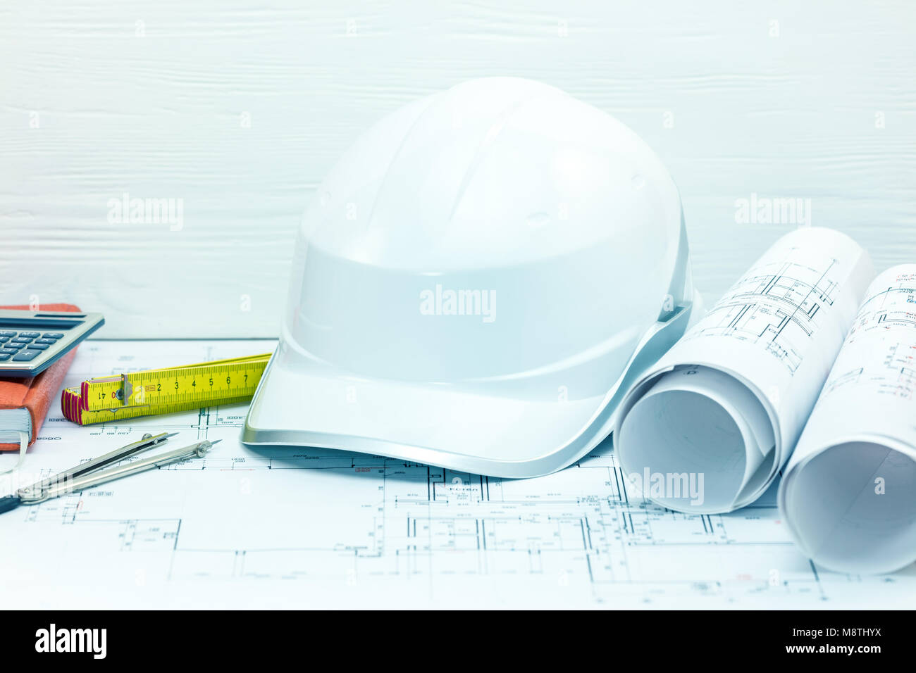 technical drawings and architectural blueprint rolls on table ...