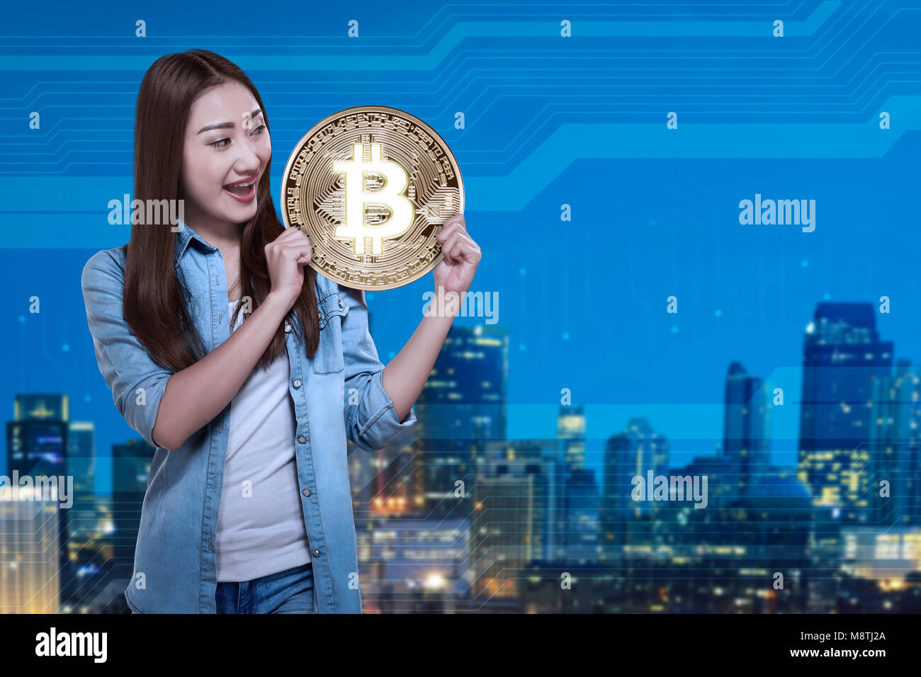 Pretty asian woman holding golden bitcoin with city night scene ...