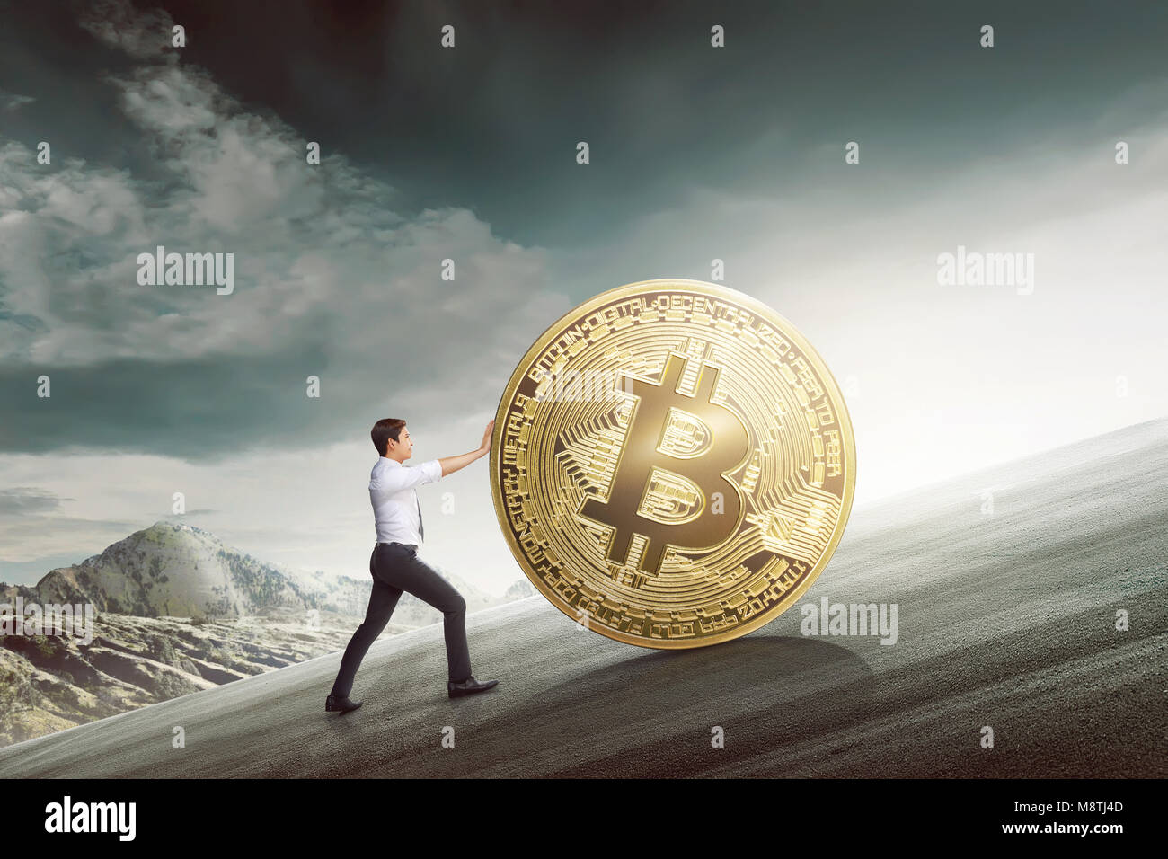 Young asian businessman pushing golden bitcoin climbing the hill with ...