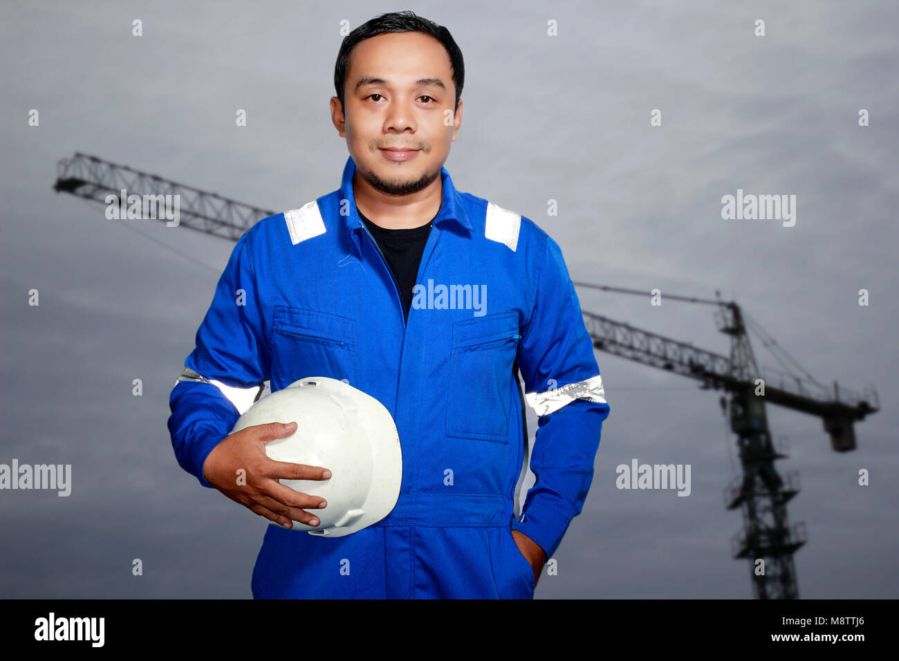 Portrait of an asian man engineer contractor with crane background ...