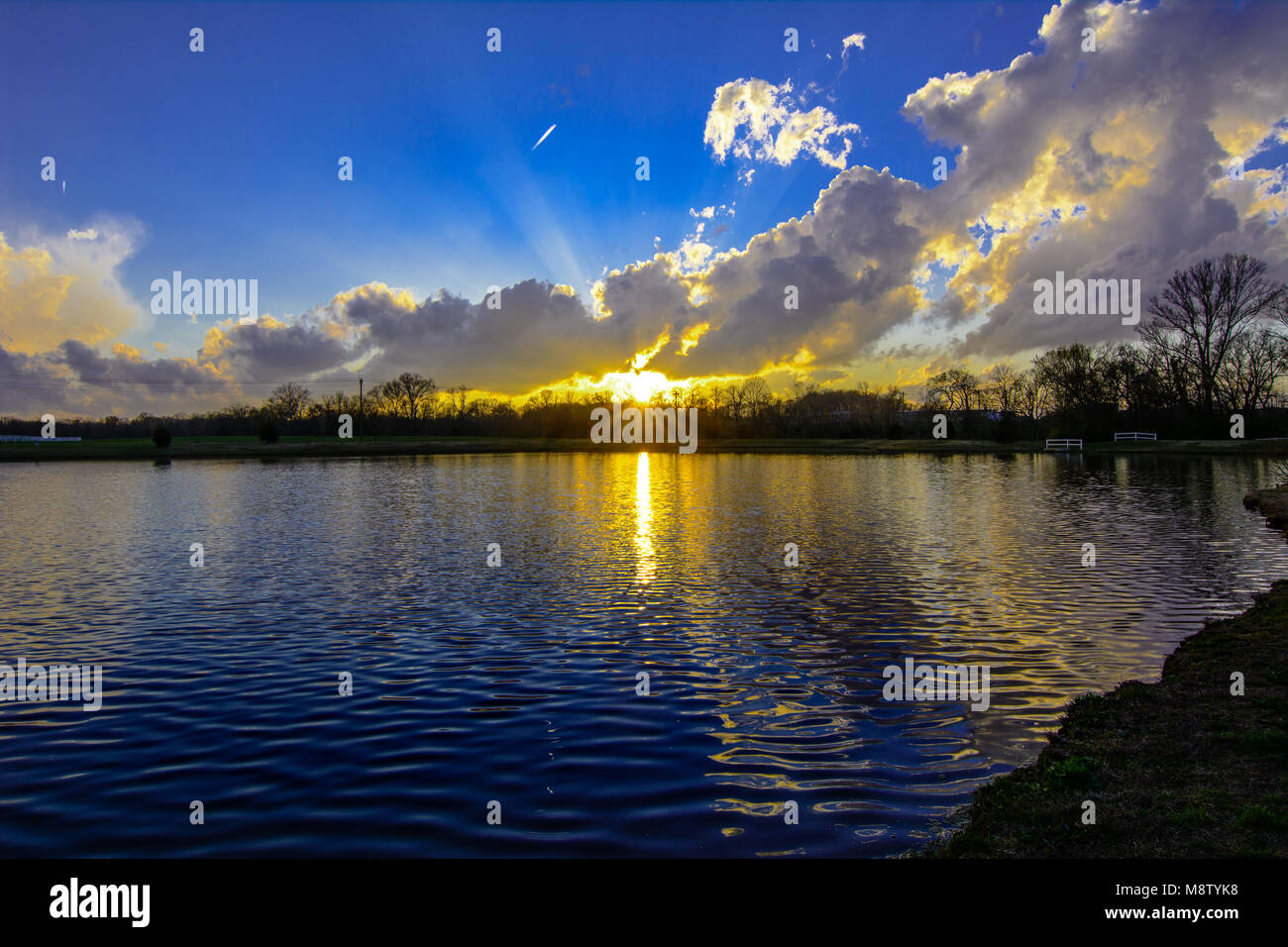 The sun and clouds reflect in a small lake at sunset Stock Photo - Alamy