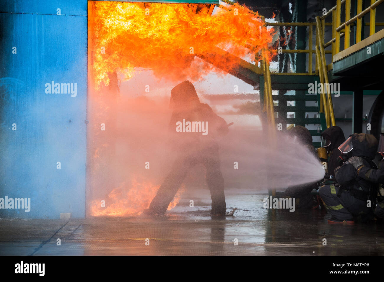 Firemen using water from hose for fire fighting at firefight training ...