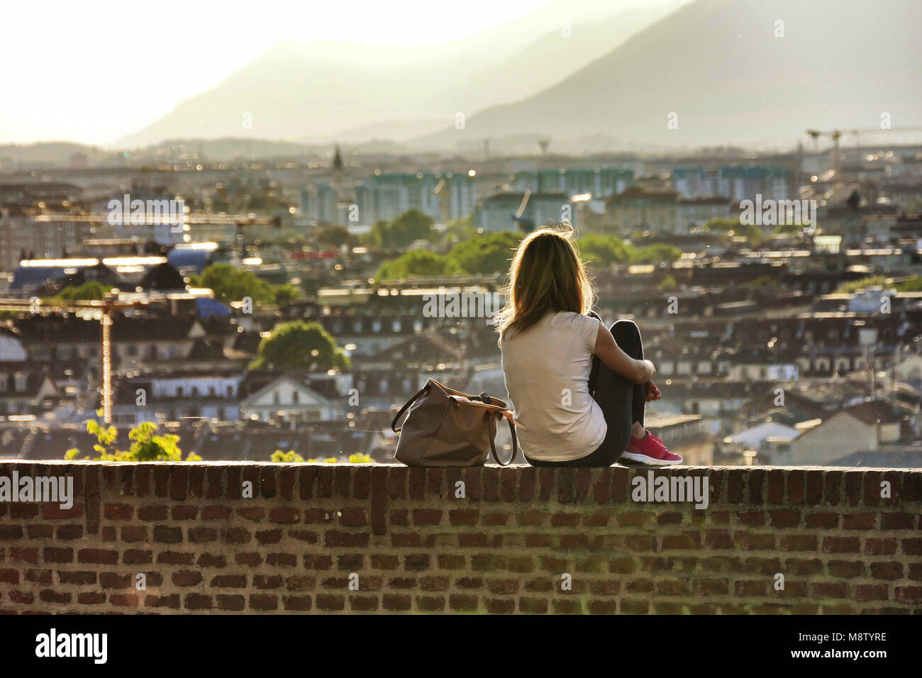 Woman alone back view watch the panorama of the city from hill ...