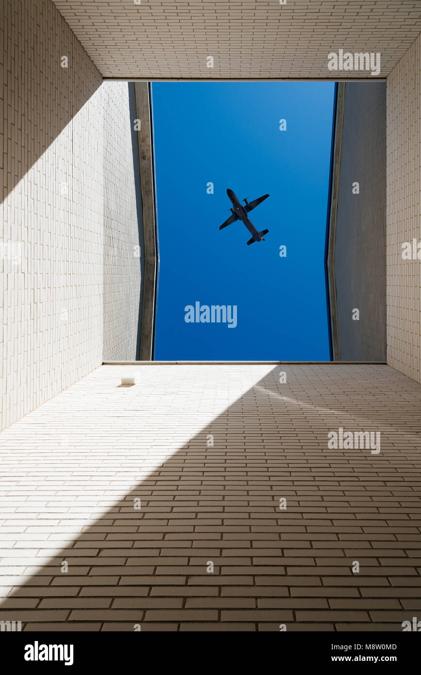 Plane flying above courtyard of modern architecture brick building ...