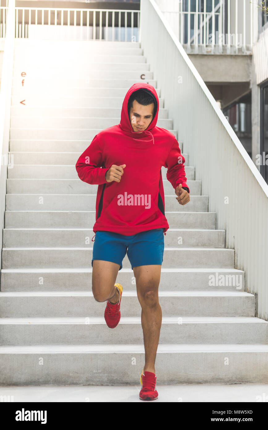 Motion blur sport man in red hood running up at steps Stock Photo - Alamy
