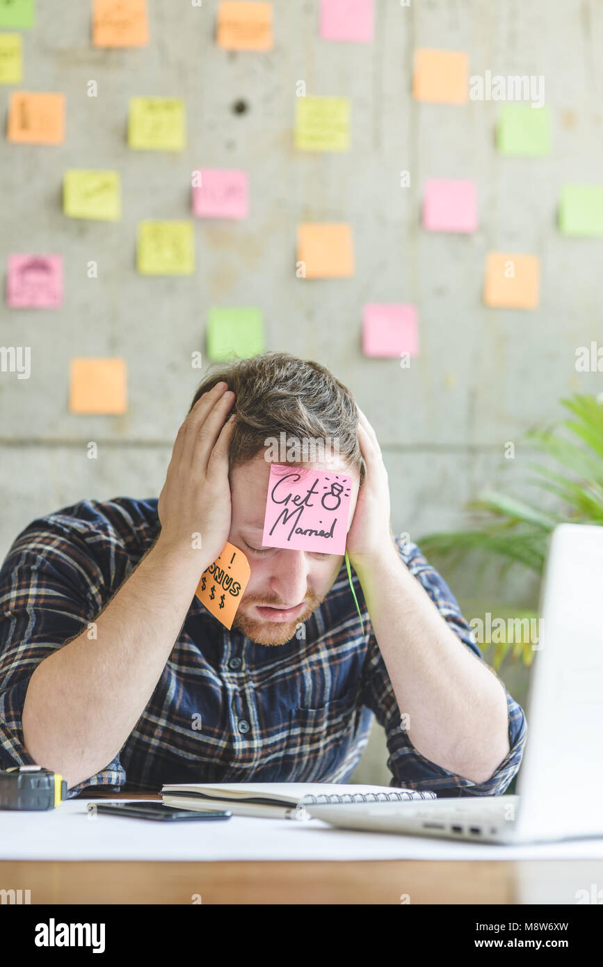 Stressed man with message on sticky notes over his face in office Stock ...