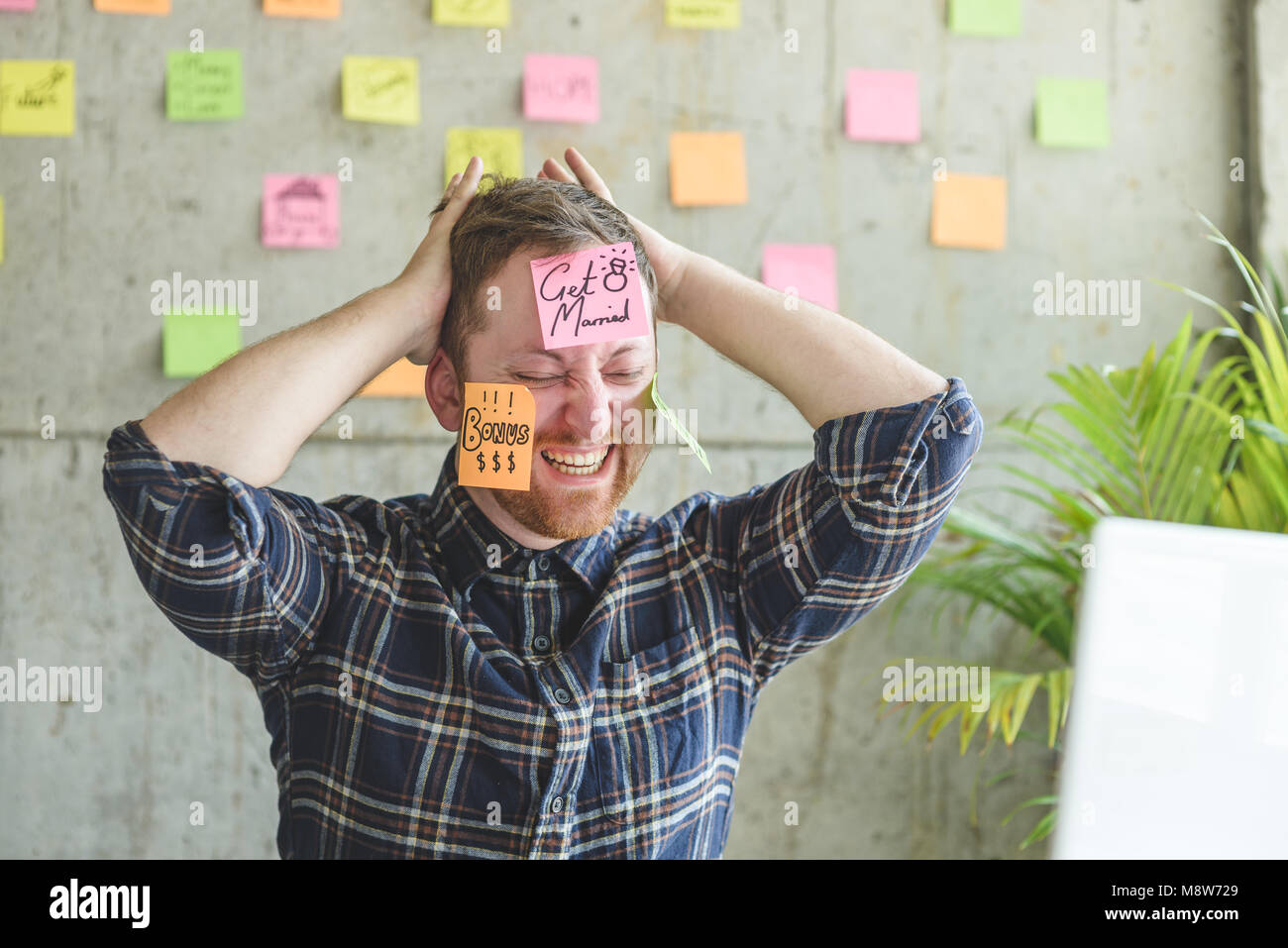 Stressed man with message on sticky notes over his face in office Stock ...