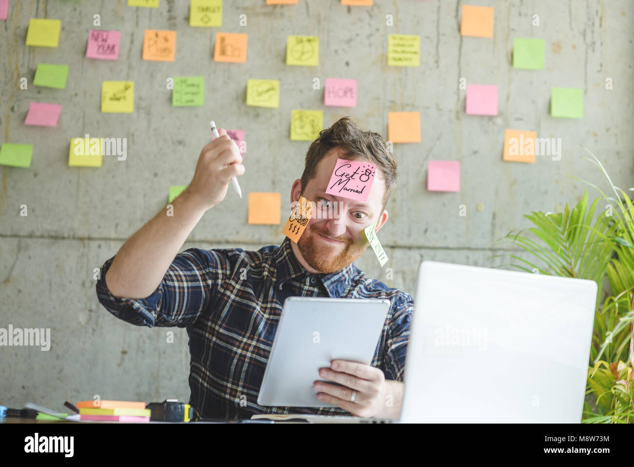 Stressed man with message on sticky notes over his face in office Stock ...