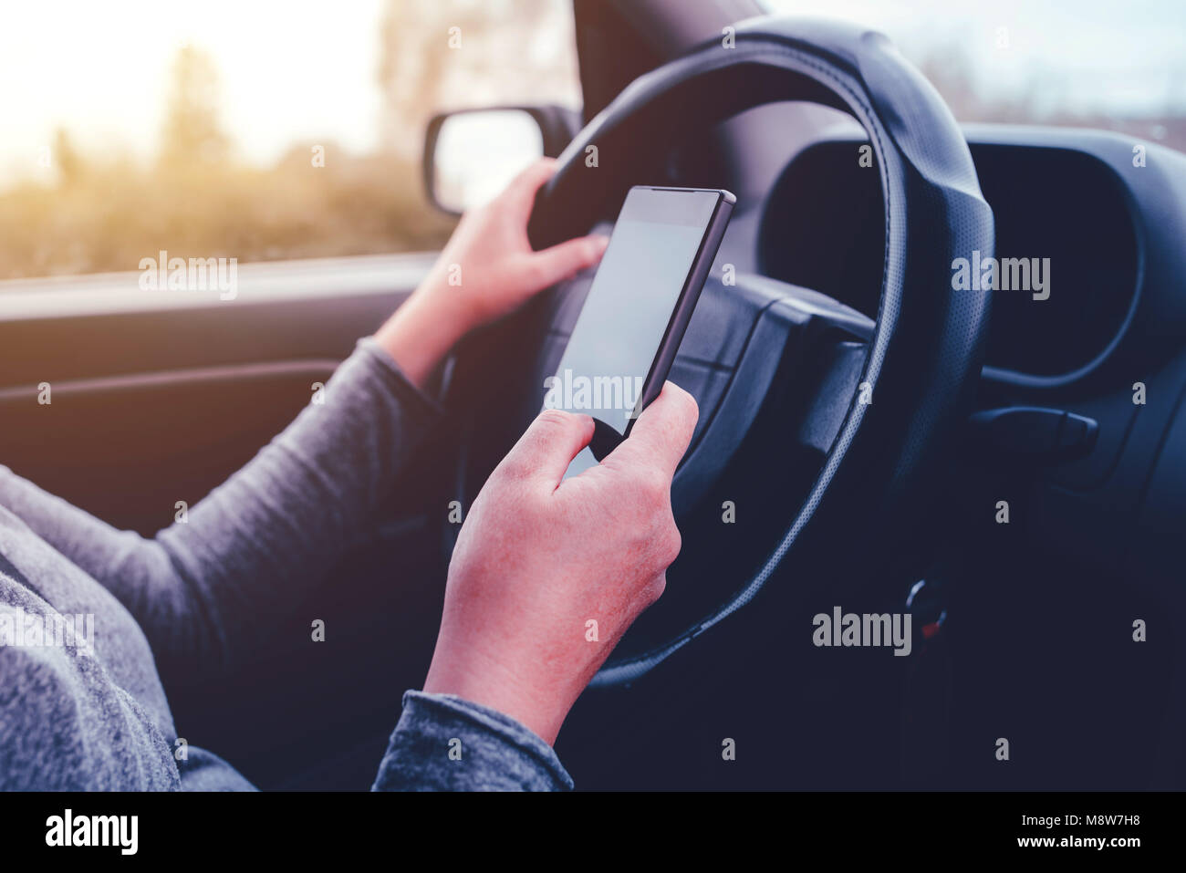 Woman simultaneously driving car and reading text message, mobile smart ...