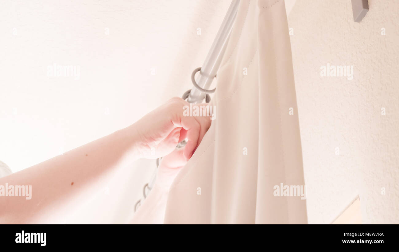 Step by step. Woman hanging curtains curtains in bedroom at new house ...